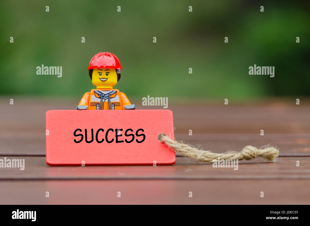 Lego women worker holding wooden tag written word succes on wooden tag ...