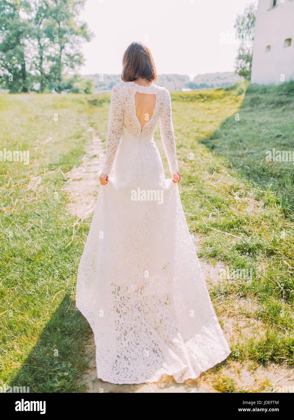 The full-length back view of the bride in the stylish long wedding ...