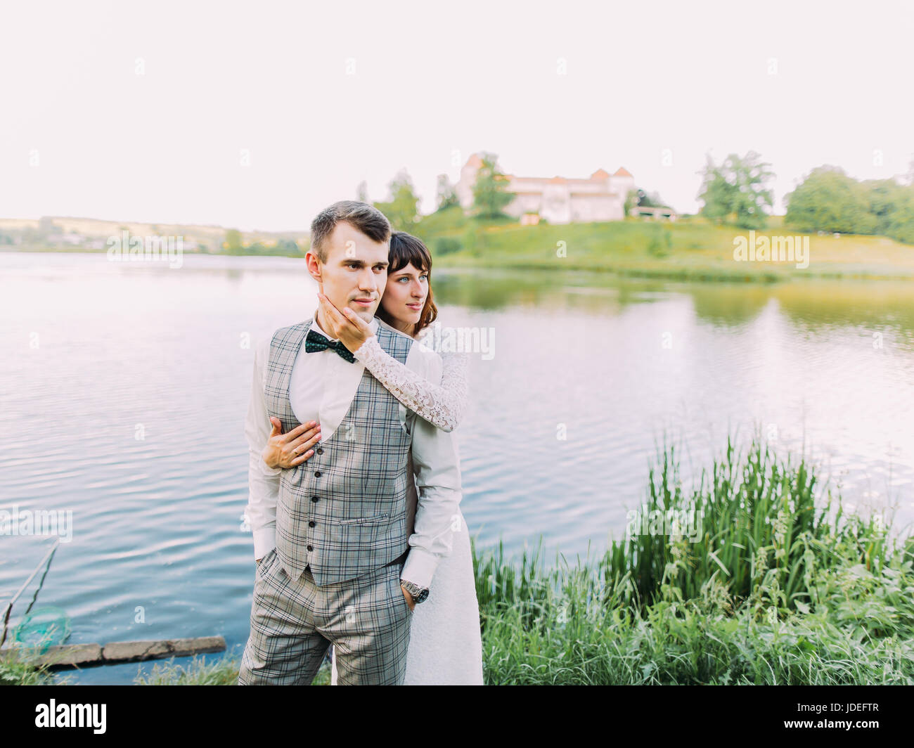 The horizontal outdoor portrait of the bride hugging the groom back ...