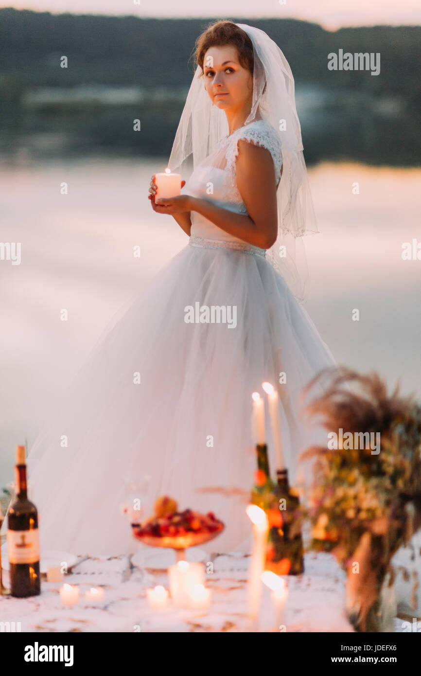 The sensitive portrait of the bride with the shining candle during the ...