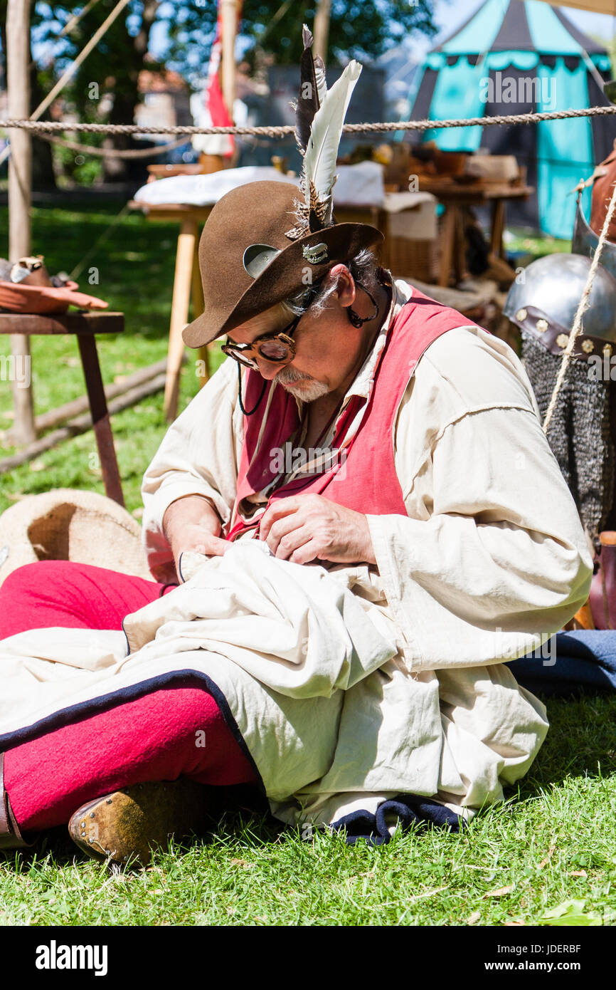 Re-enactment, Medieval weaver, with glasses, sitting on grass while ...