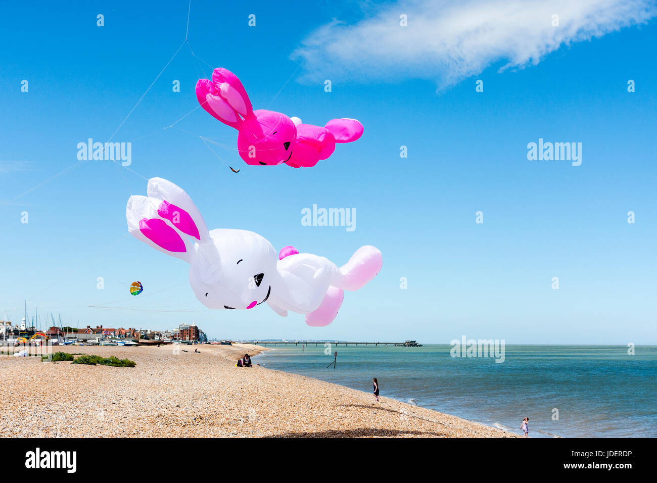 Two bunny shaped inflated kites, one white, other pink, flying against ...