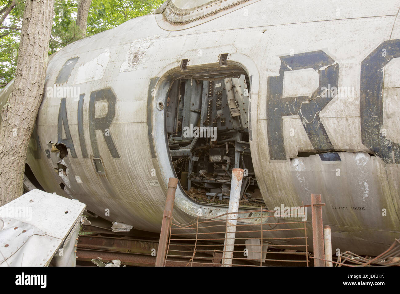 Nose cone of wrecked US Air Force fighter jet in trees of junkyard ...