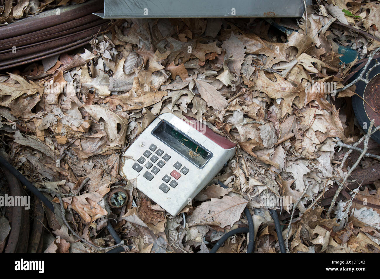 Old obsolete calculator in dry leaves among rusting scrap metal in ...
