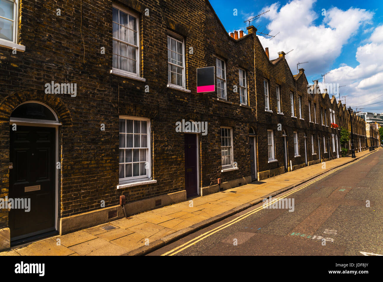 Typical old English buildings, low brick buildings across a narrow ...