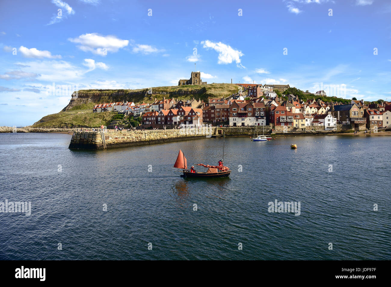 View of boat returning to Whitby Harbour and gothic church in ...