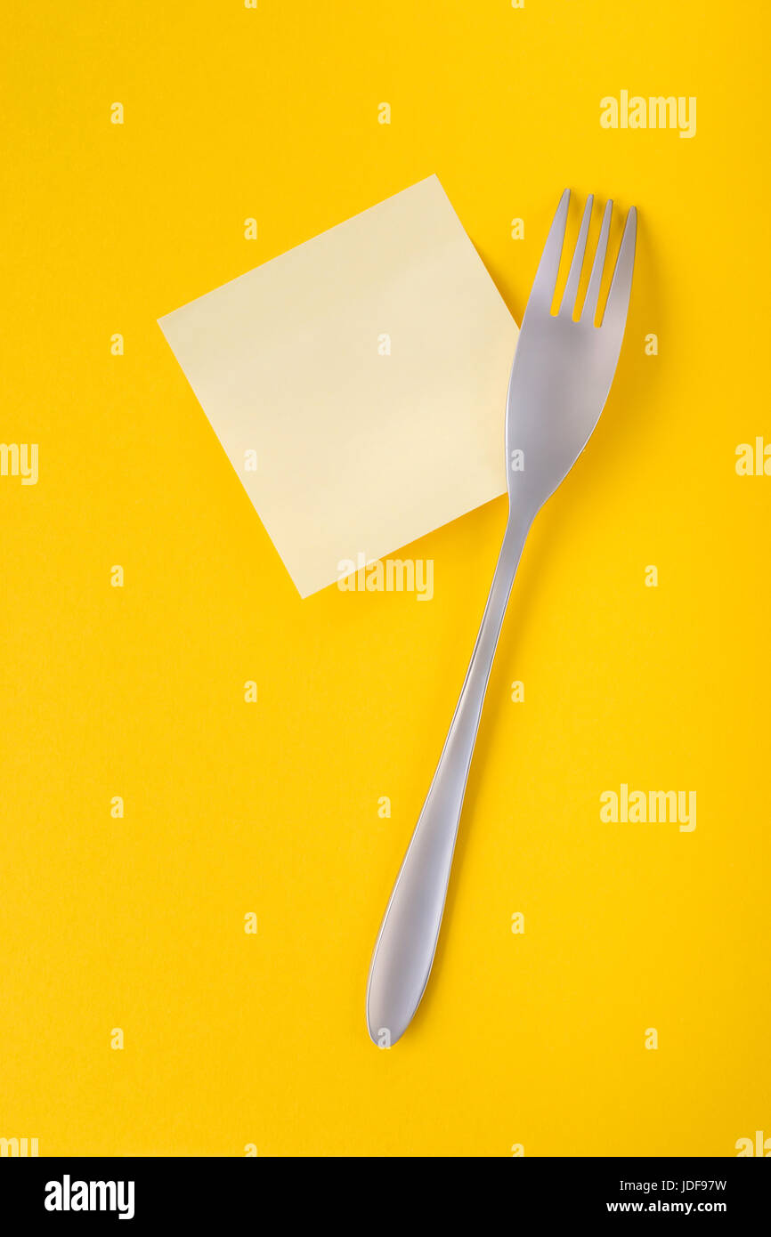 Fork and stick note on yellow background. Template with copy space ...