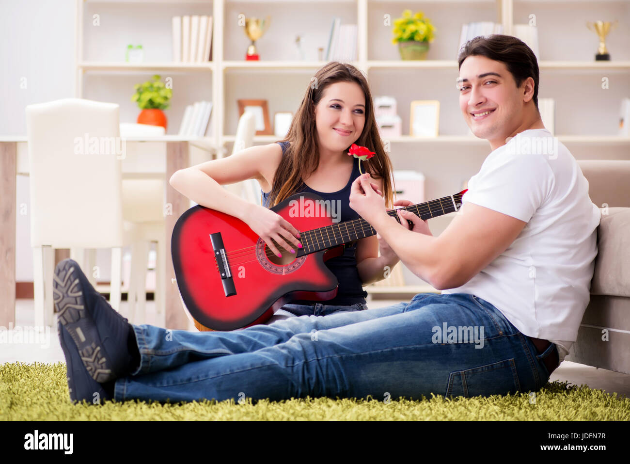 Romantic pair playing guitar on floor Stock Photo - Alamy