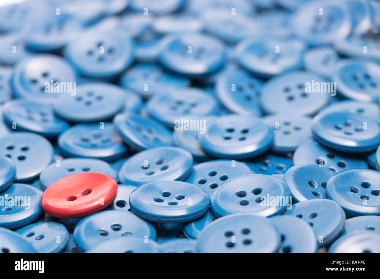 One red button on a heap of blue buttons left based Stock Photo - Alamy