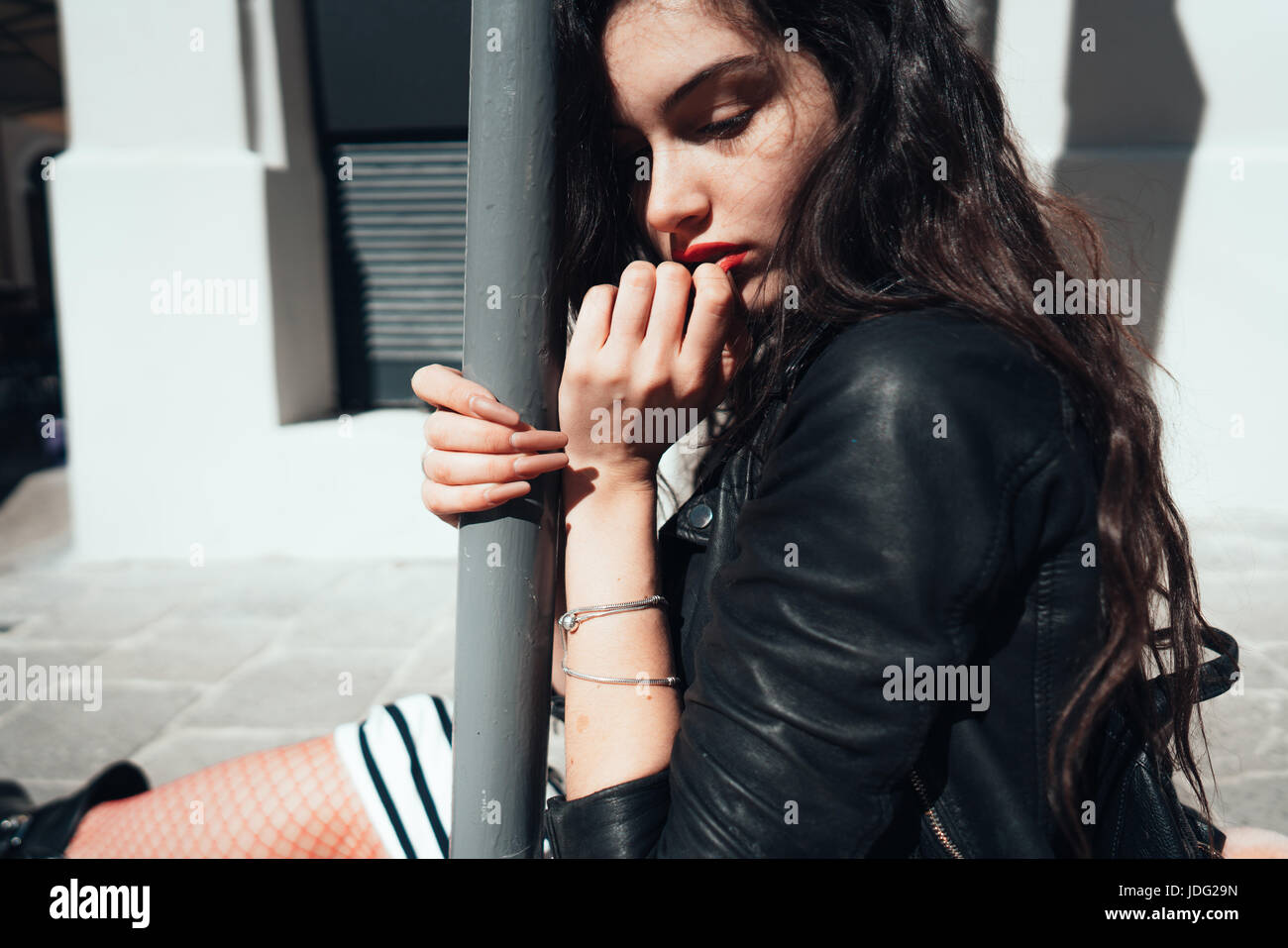 Beautiful fashionable lady sitting on old street Stock Photo - Alamy