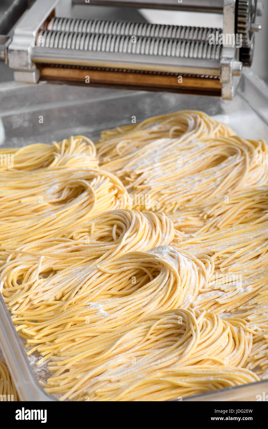Bundles of freshly made Italian spaghetti pasta on a white plastic tray ...