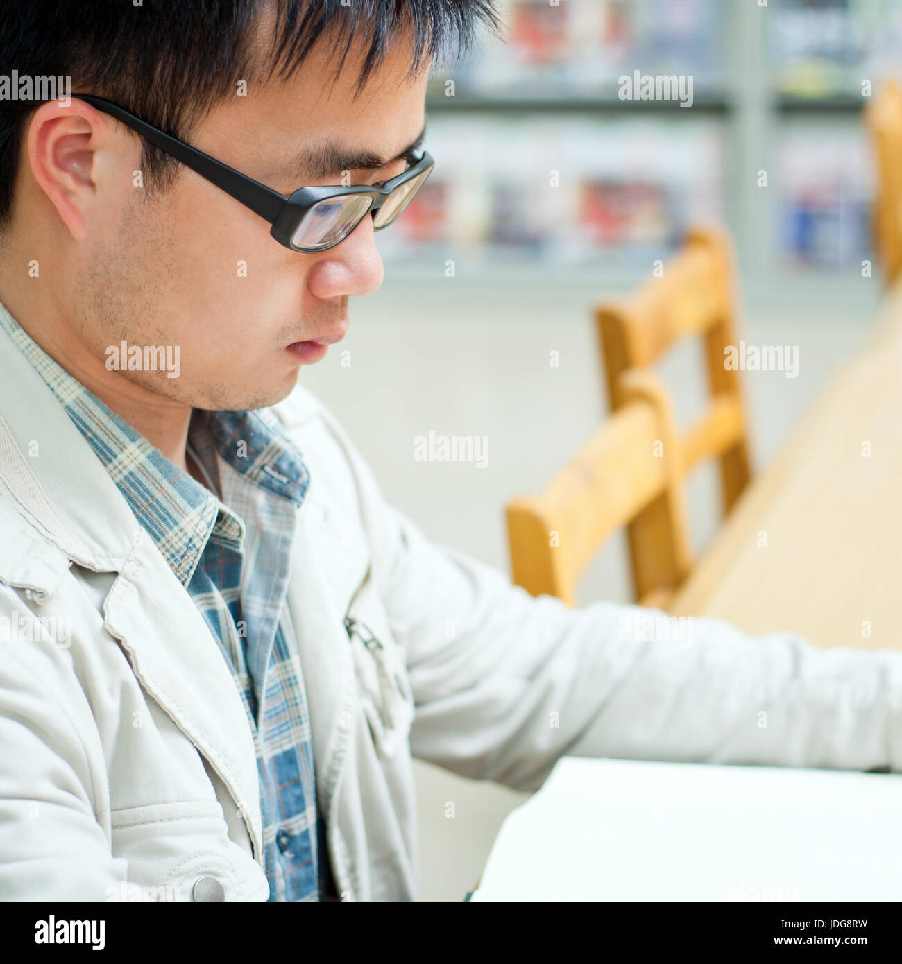 Handsome man sitting and reading in library Stock Photo - Alamy