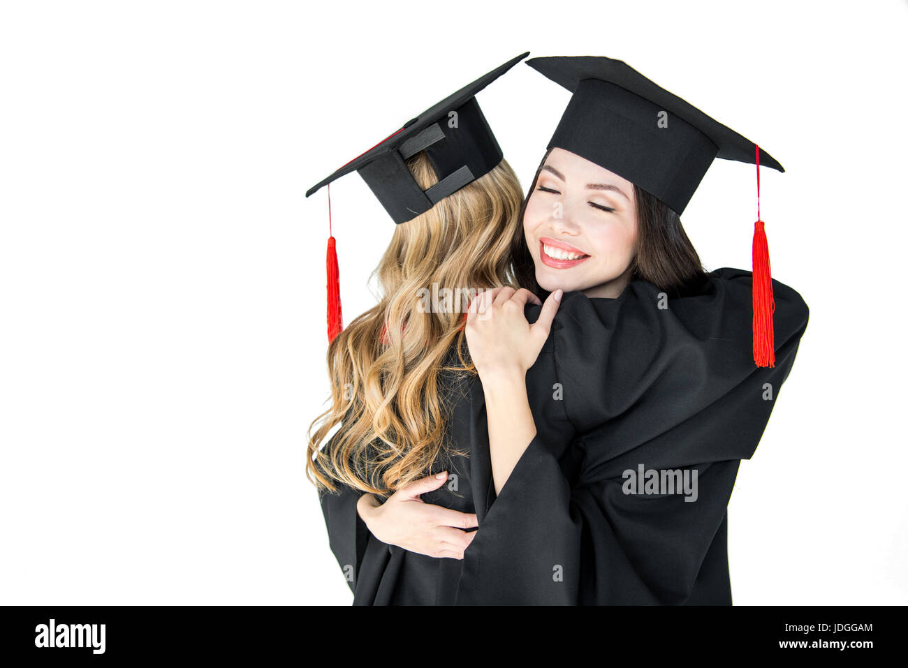 attractive happy students in graduation caps hugging isolated on white ...