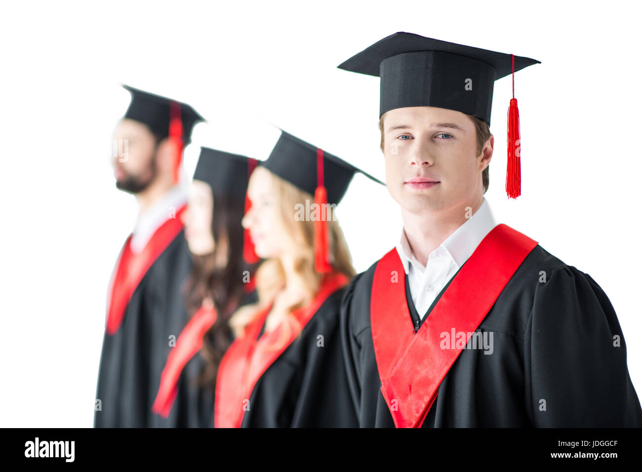 young student in graduation cap with diploma, with friends behind ...