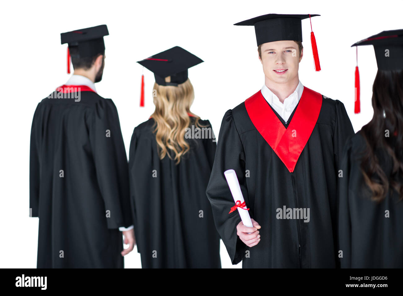 young student in graduation cap with diploma, with friends behind ...