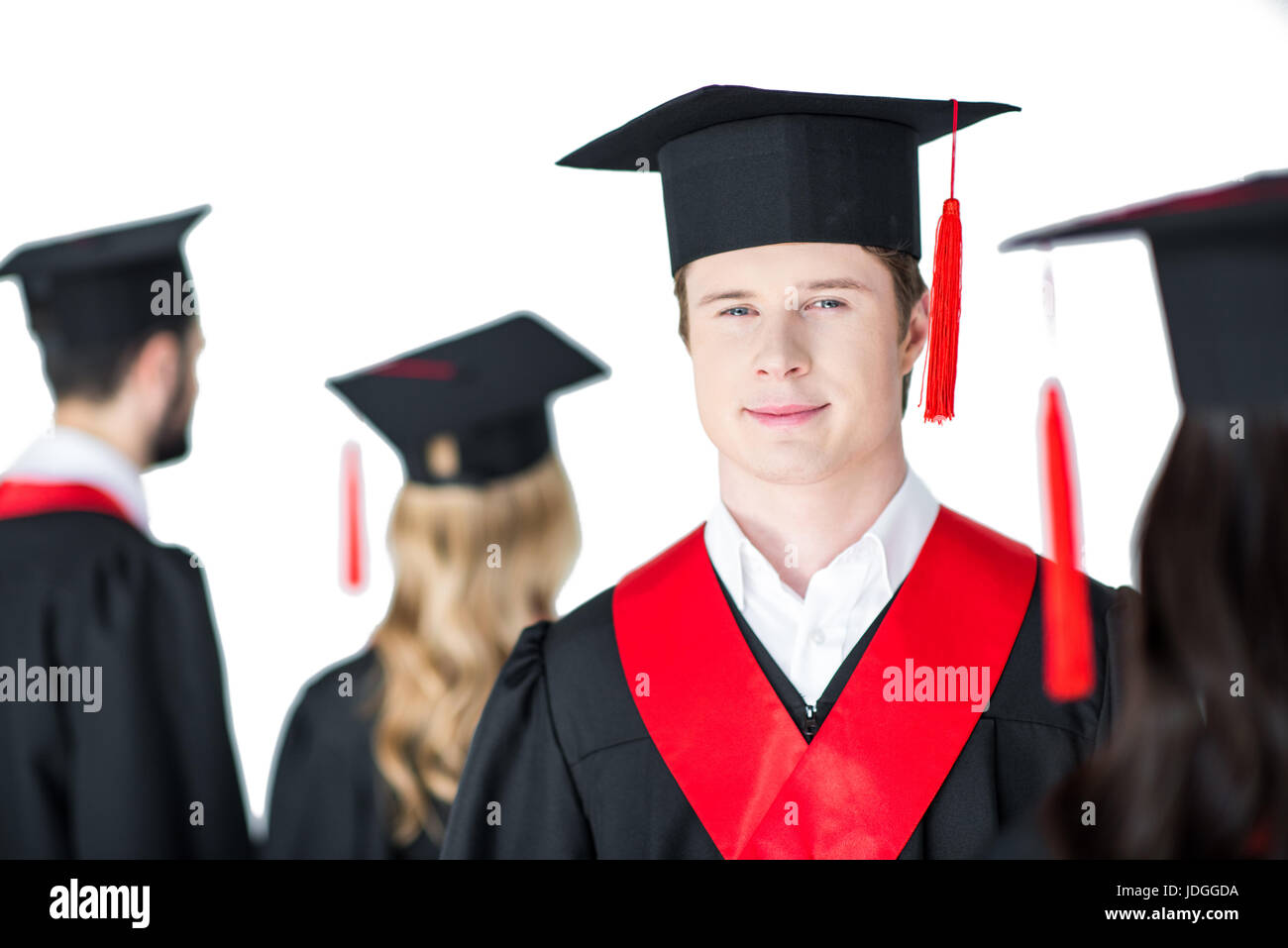 young student in graduation cap with diploma, with friends behind ...