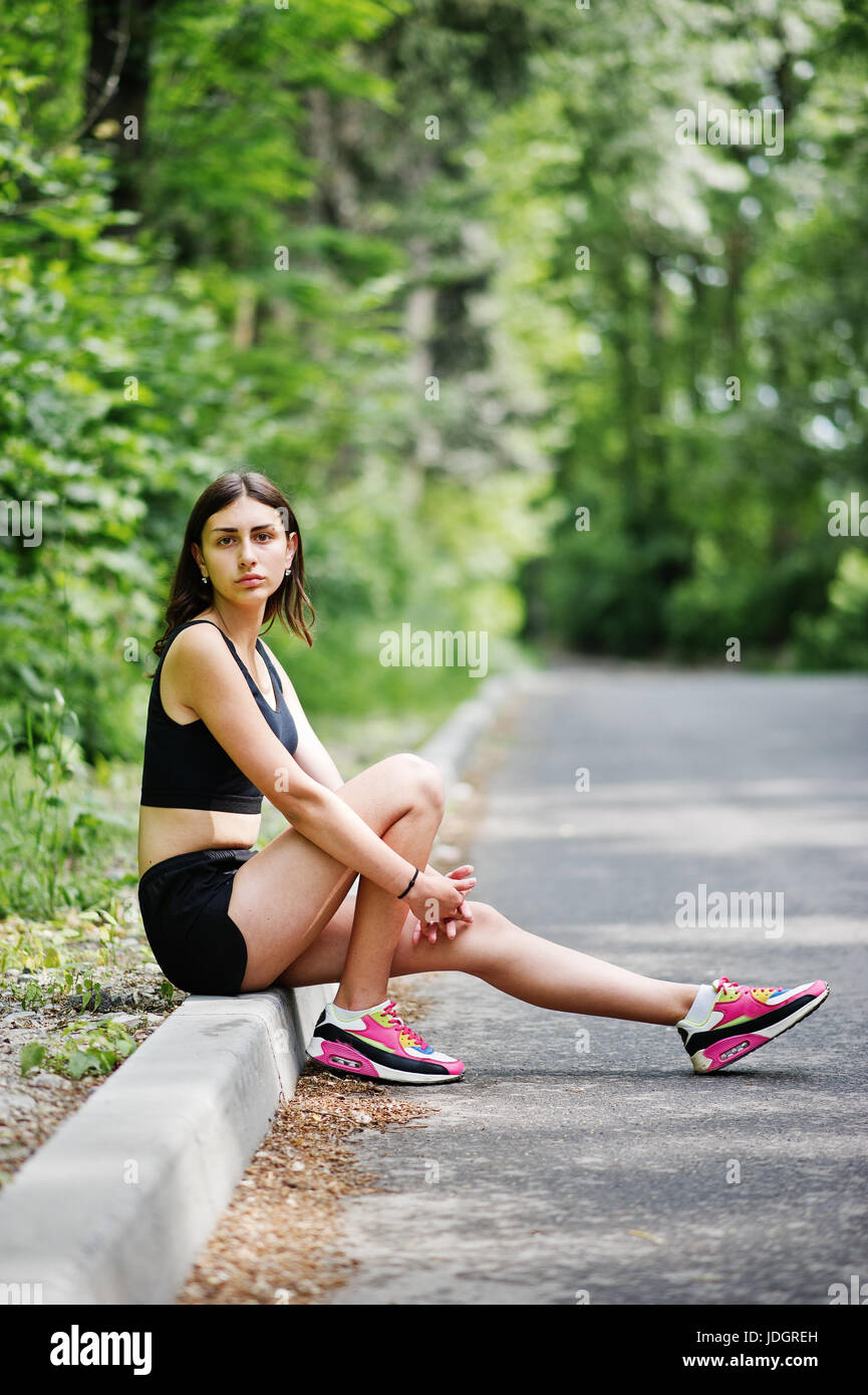 Sport girl at sportswear having rest in a green park after training at ...