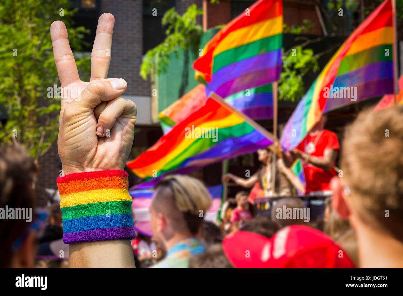 Supporting hands make peace sign in front of a rainbow flags flying on ...