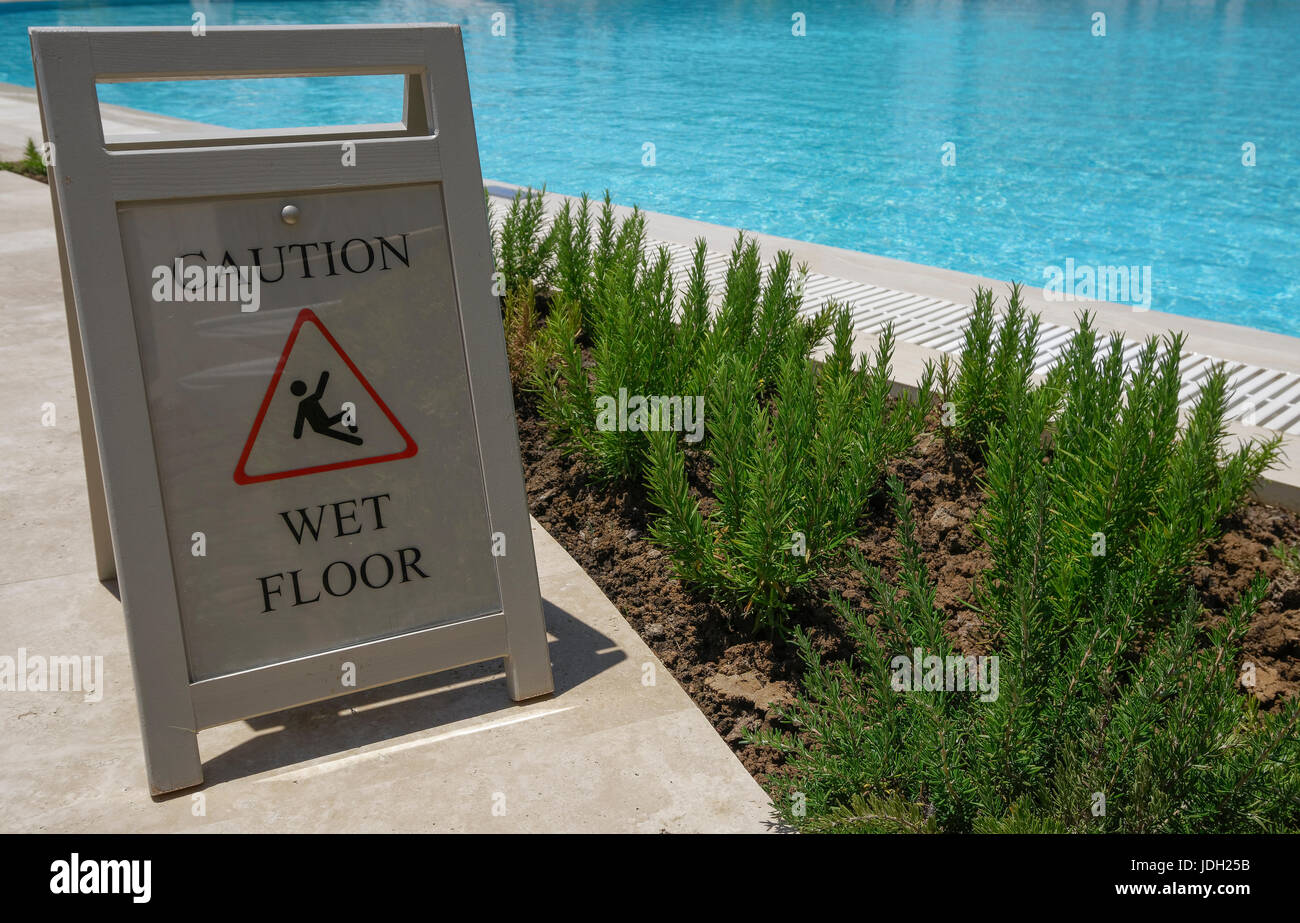 Open air poolside with turquoise water and slippery when wet sign Stock ...