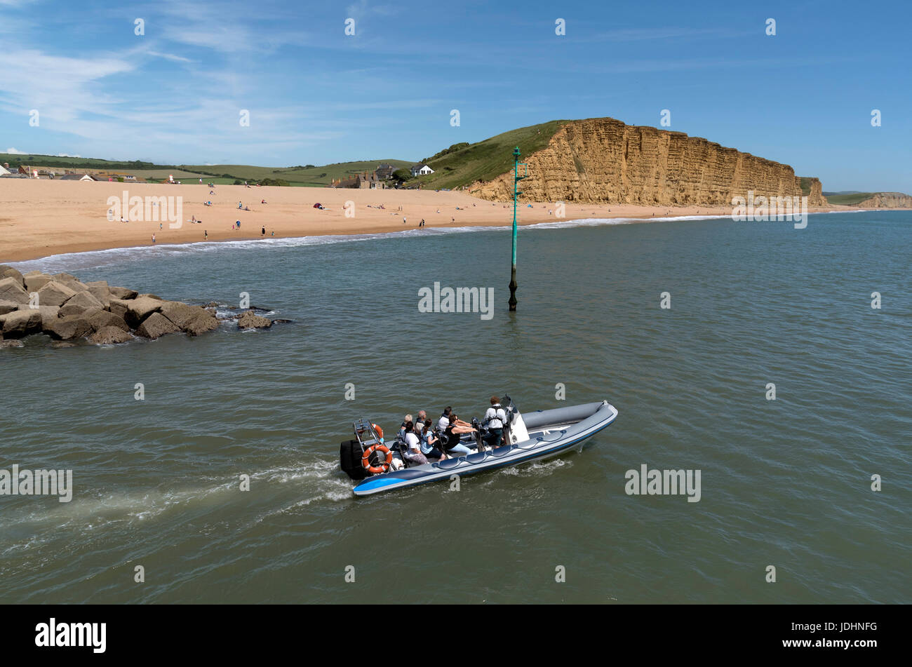 A tour boat viewing the beach and golden strata of the East Cliff at ...