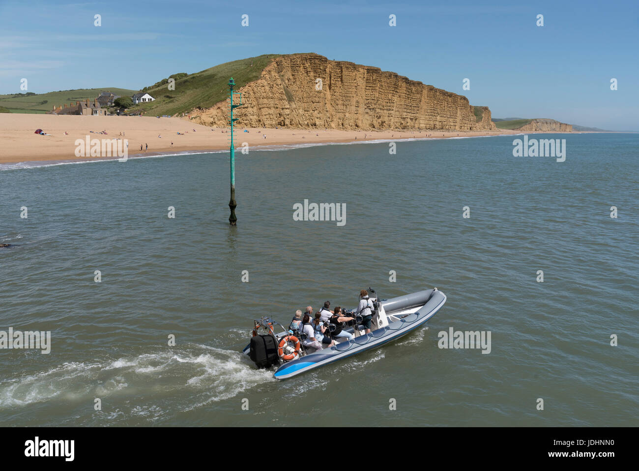 A tour boat viewing the beach and golden strata of the East Cliff at ...