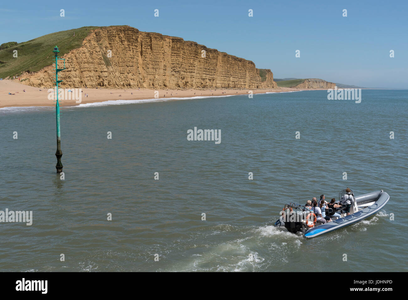 A tour boat viewing the beach and golden strata of the East Cliff at ...