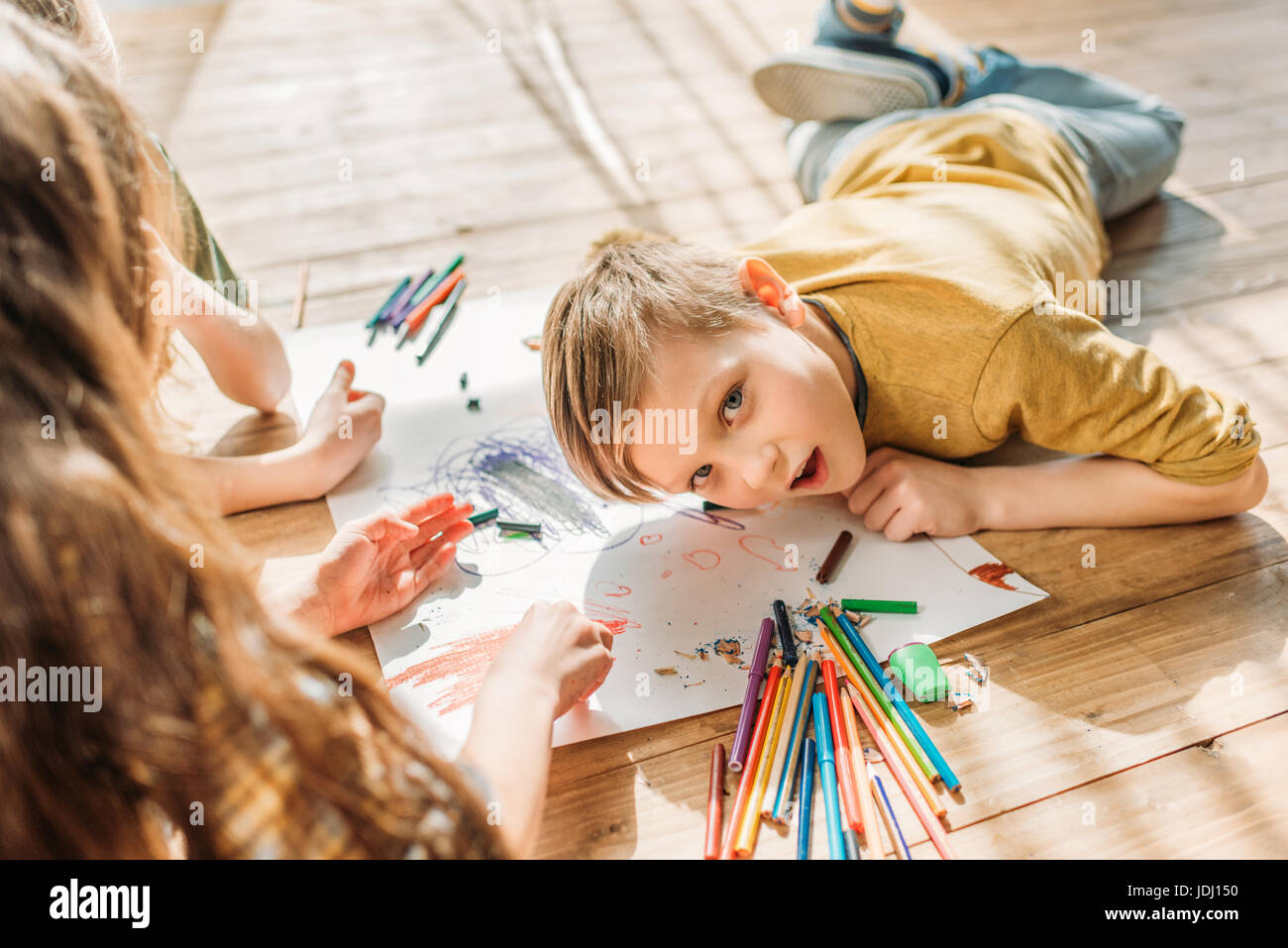 cute kids drawing on paper with pencils while lying on floor Stock ...