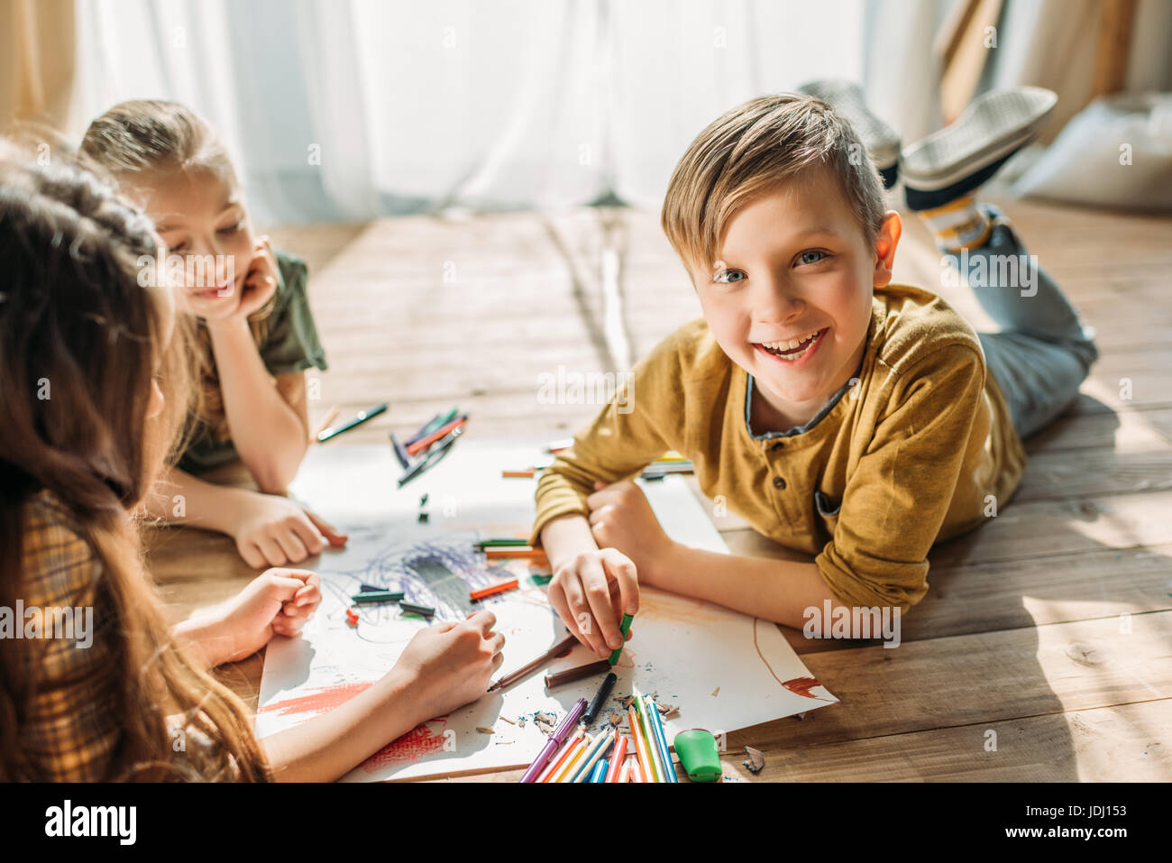 cute kids drawing on paper with pencils while lying on floor Stock ...