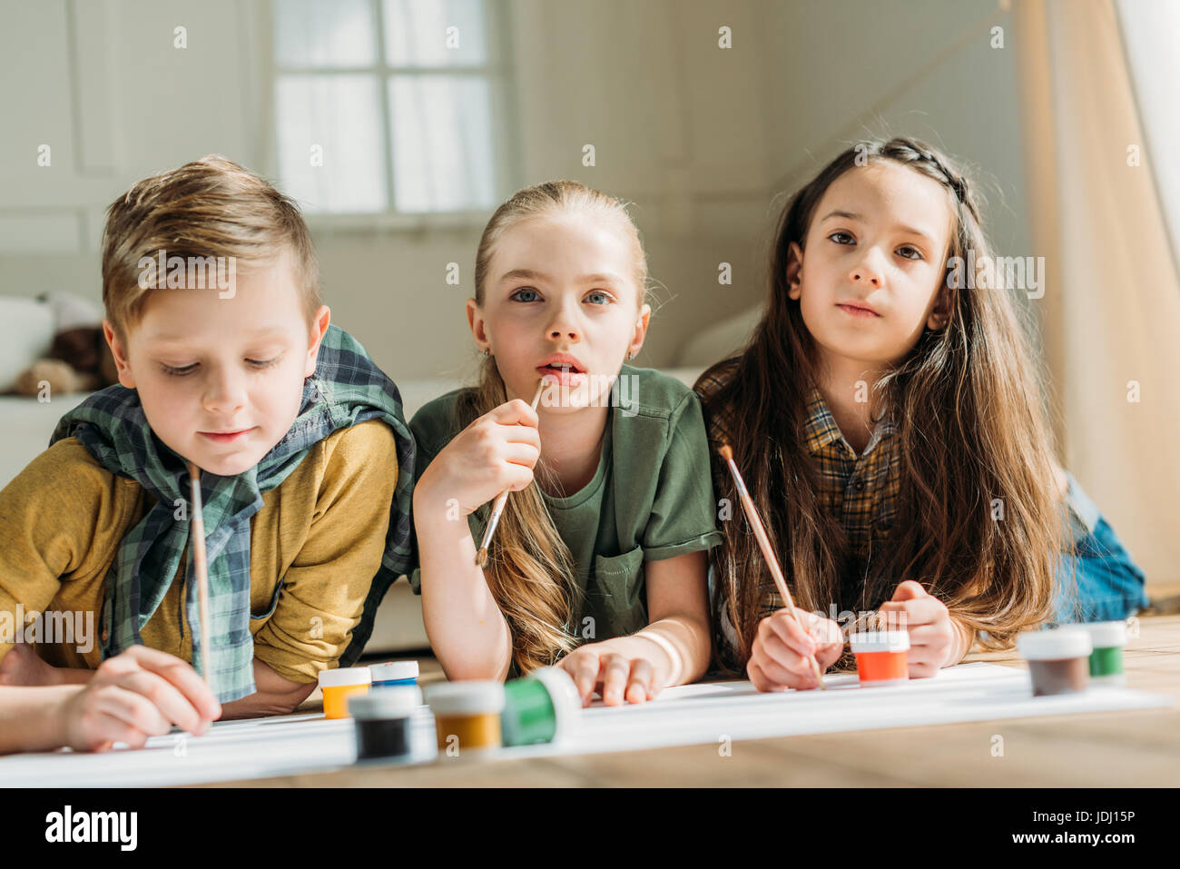 cute kids painting on paper with while lying on floor at home Stock ...