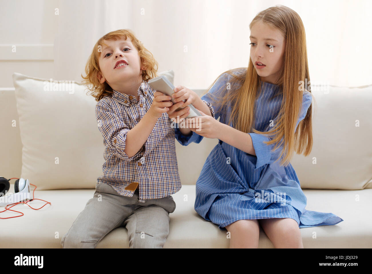 Adorable active children fighting for remote Stock Photo - Alamy