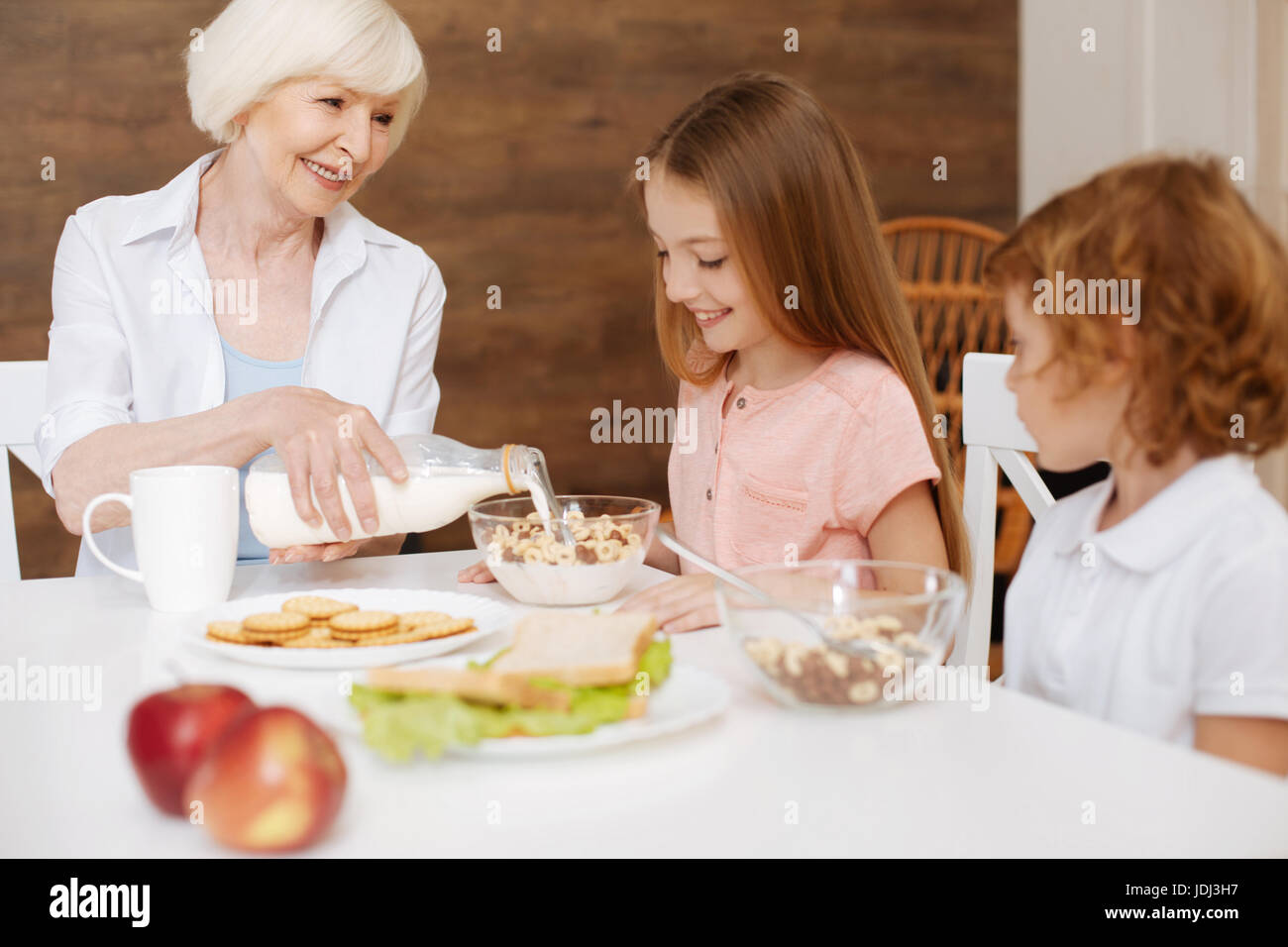Cute caring grandma pouring milk in cereal Stock Photo - Alamy