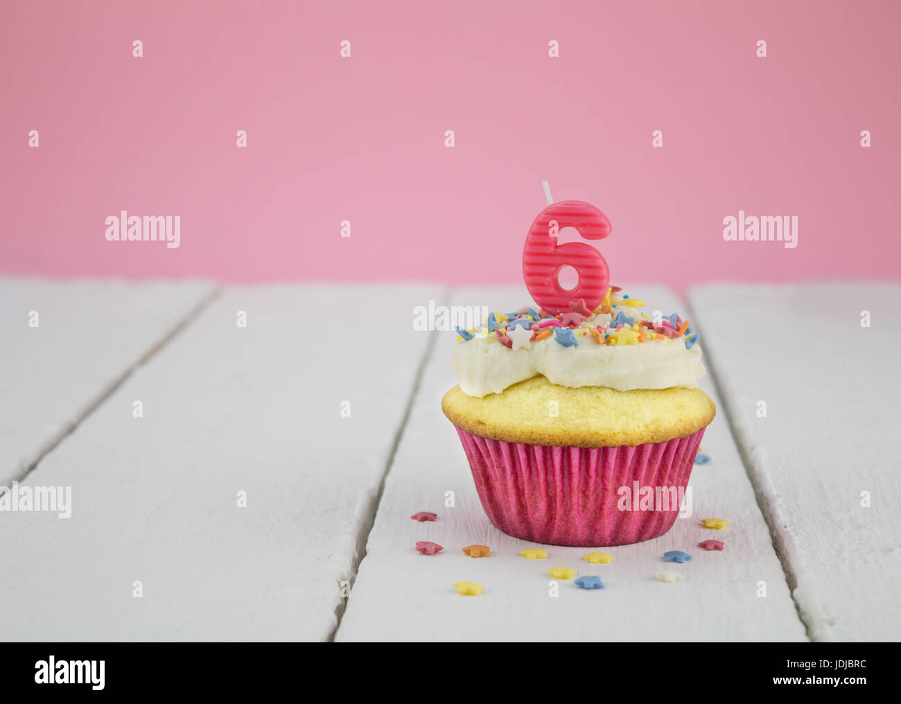 Happy birthday cup cake with pink number 6 candle on white wood table ...