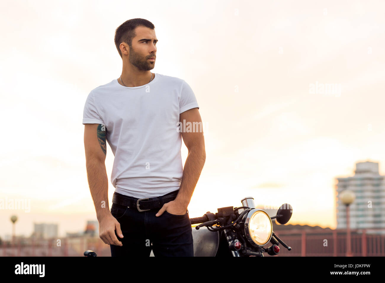 Sporty biker handsome rider male in white blank t-shirt walk away from ...
