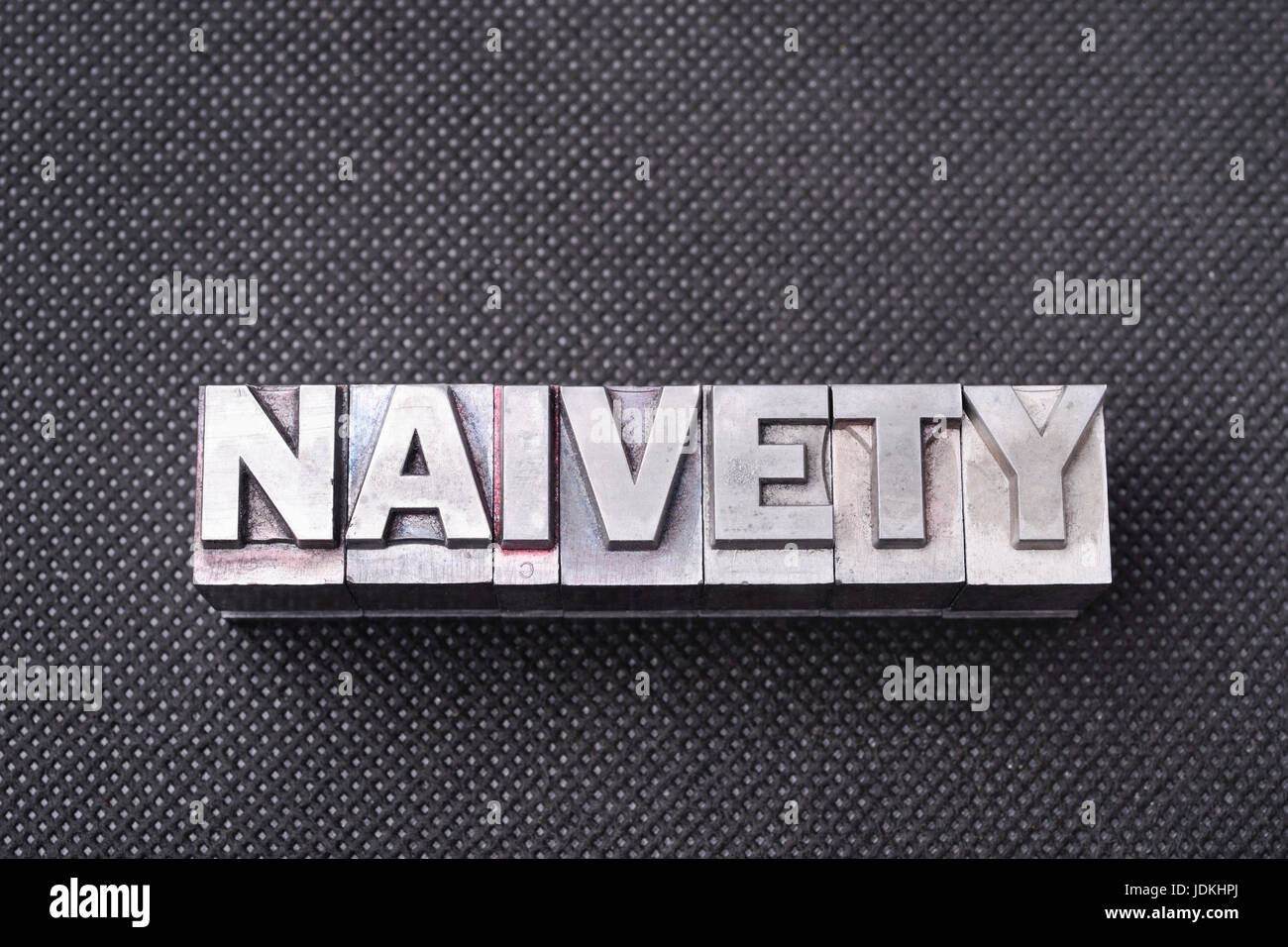 naivety word made from metallic letterpress blocks on black perforated ...