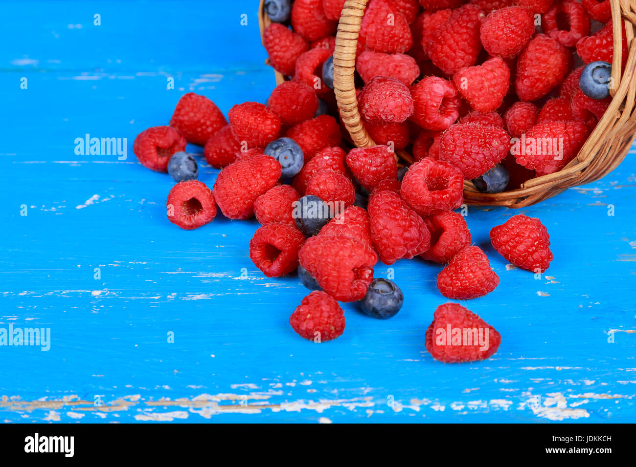 Fresh berry fruit pile in basket with leaves placed on old wooden ...