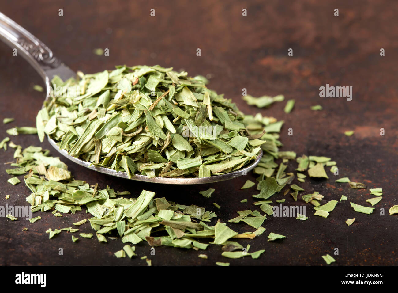 Spoon filled with dried tarragon on rusty background Stock Photo - Alamy
