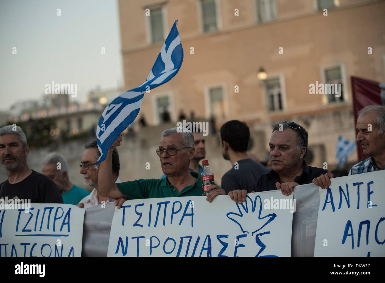Protesters wave Greek flags and placards as they shout slogans. More ...