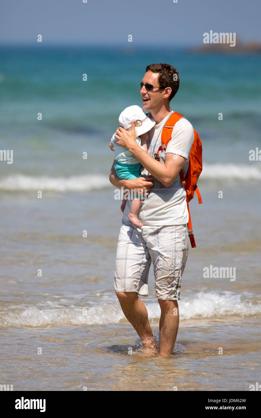 A man protecting a young baby clinging to his chest from the harsh ...