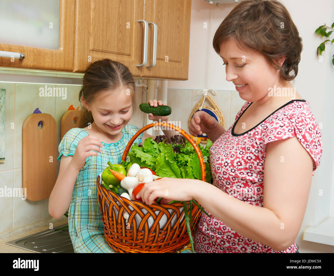 Mother and daughter with basket of vegetables and fresh fruits in ...