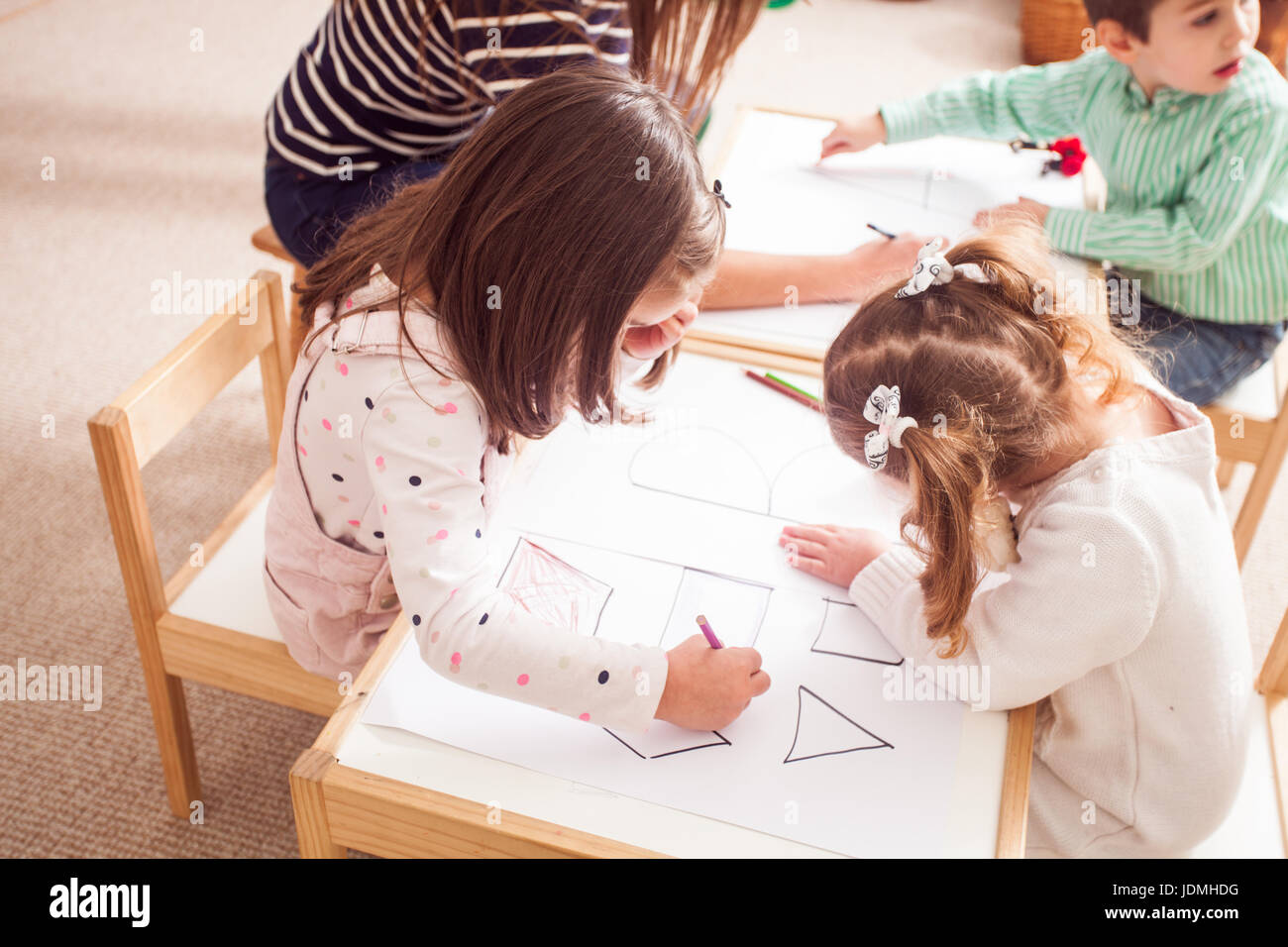 Overhead view of children in kindergarten learn letters and shapes ...
