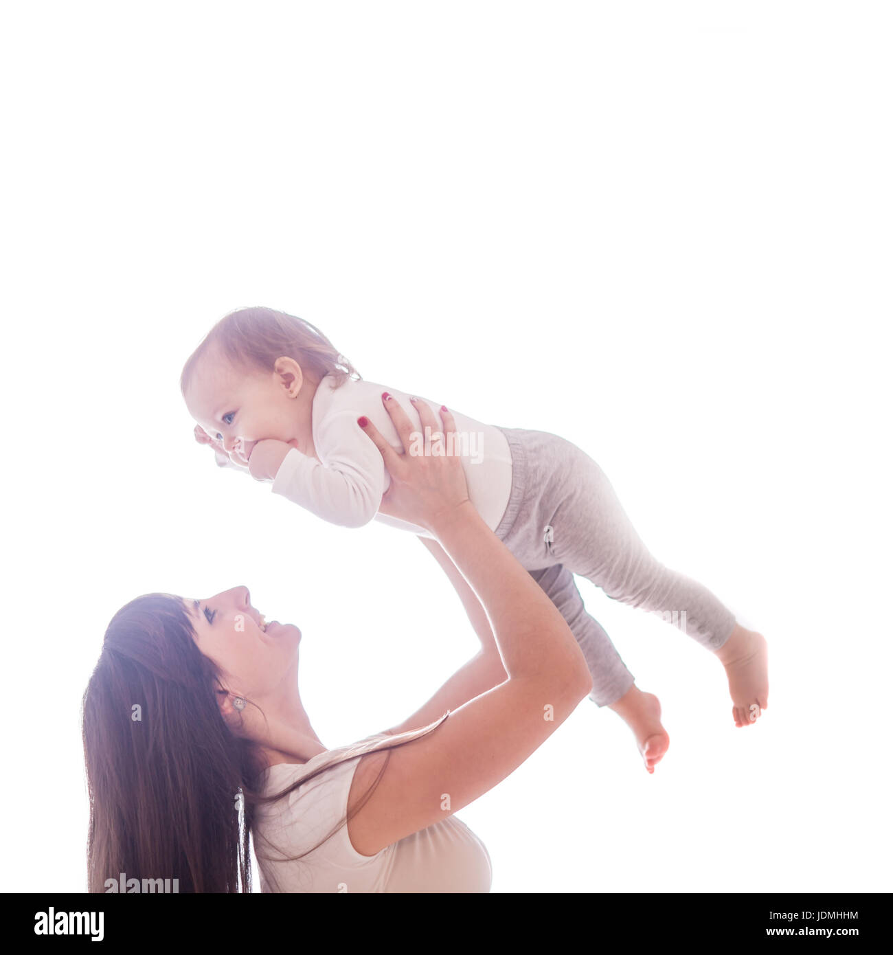 Young mother play with her little baby girl, opposite the window in the ...