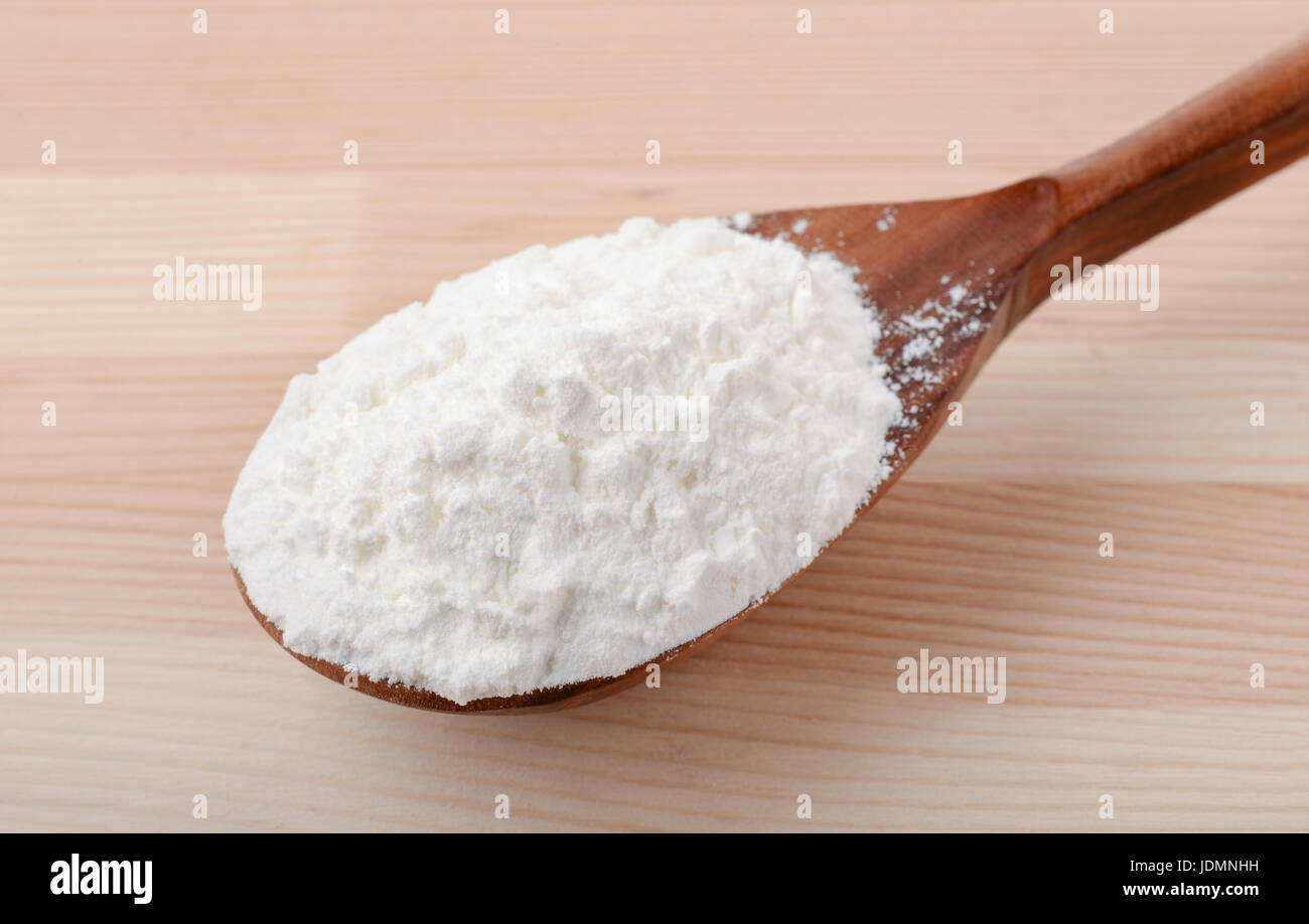Spoon of corn starch on wooden background Stock Photo - Alamy