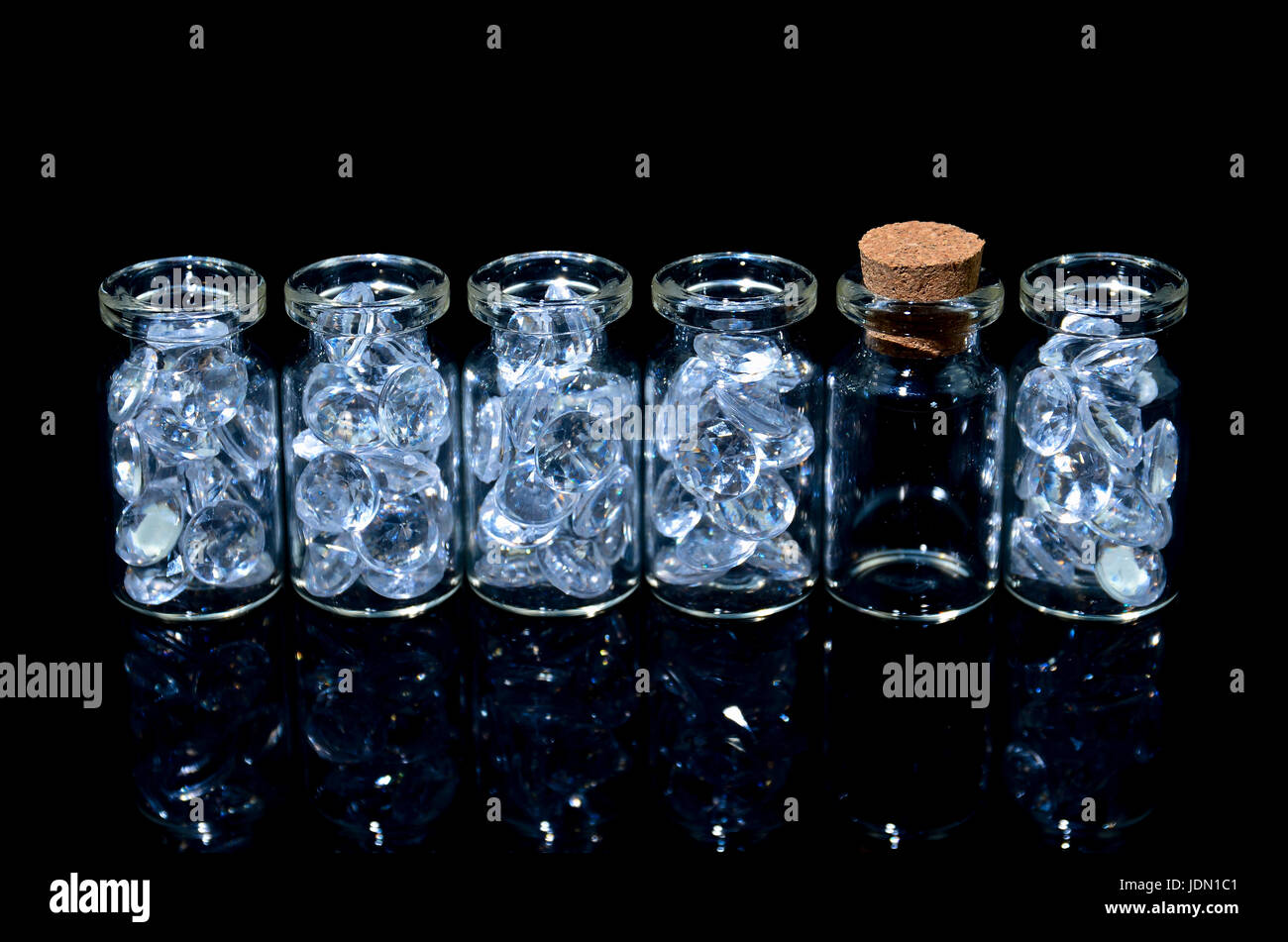 Diamonds in small jar and one empty jar against black background Stock ...