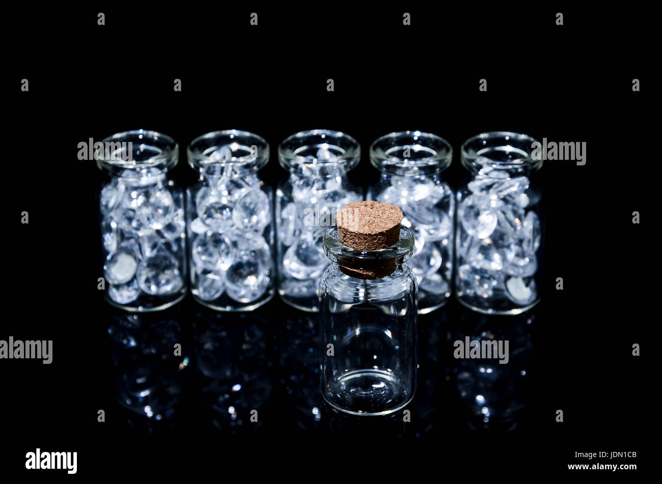 Diamonds in small jar and one empty jar against black background Stock ...