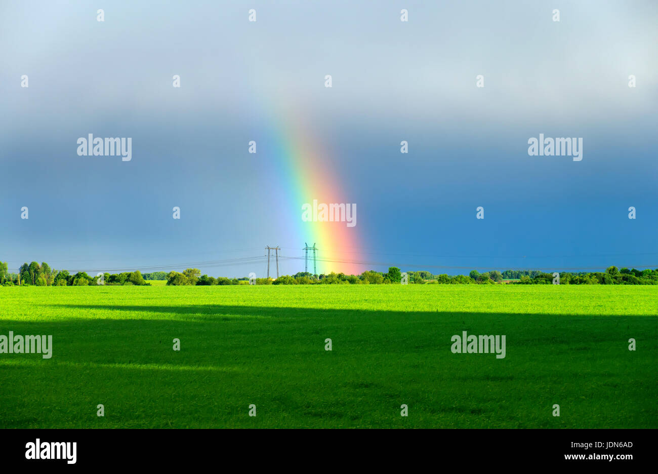 beautiful landscape with green meadow and a bright rainbow far away in ...