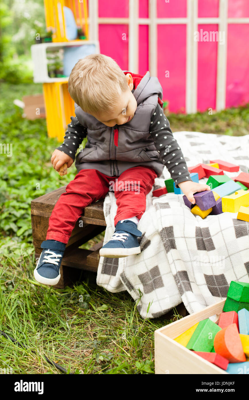 Little boy building something using wooden colorful toy block sitting ...