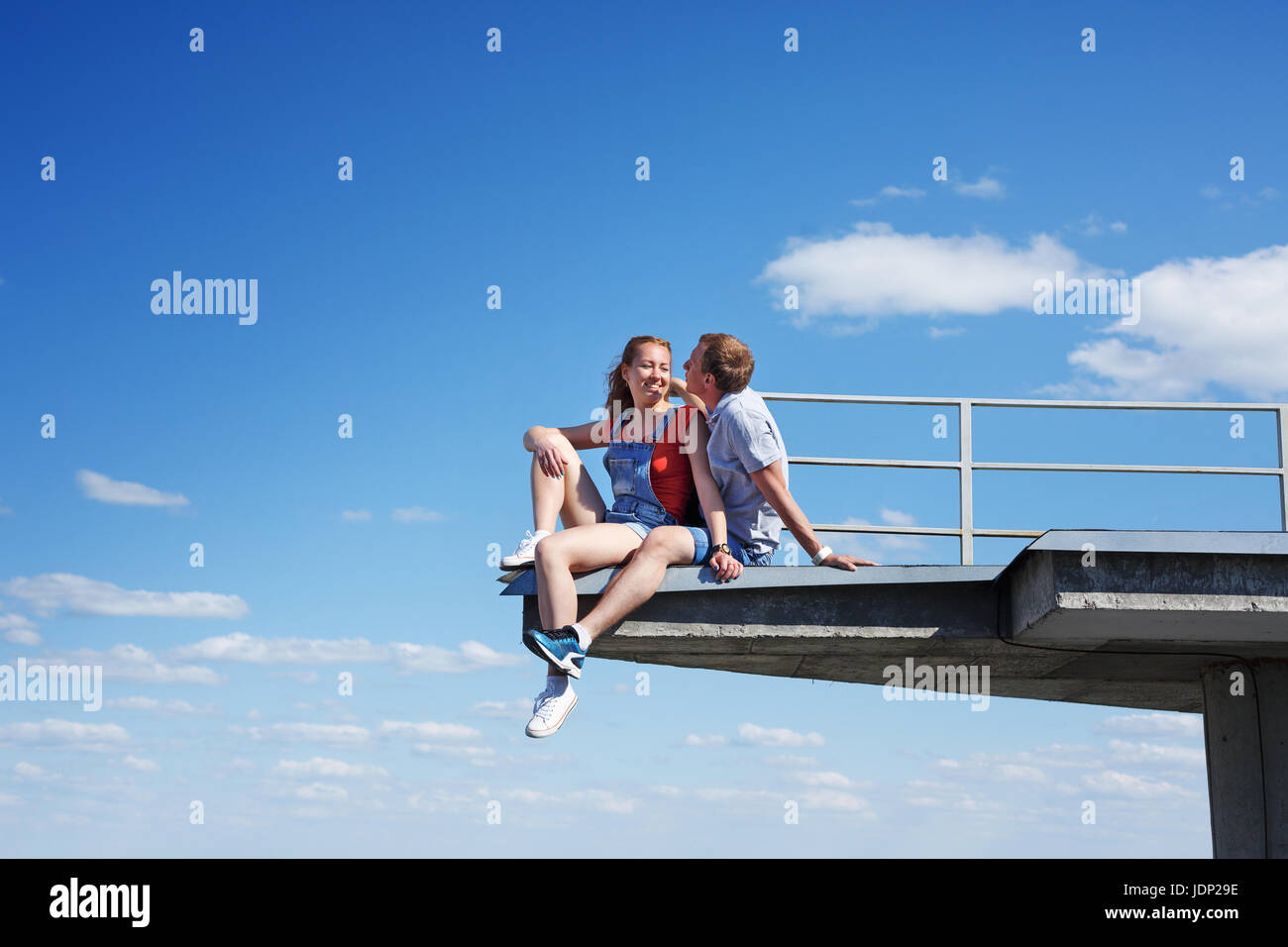 roofer couple in love sitting on the edge of the roof. Romance and ...