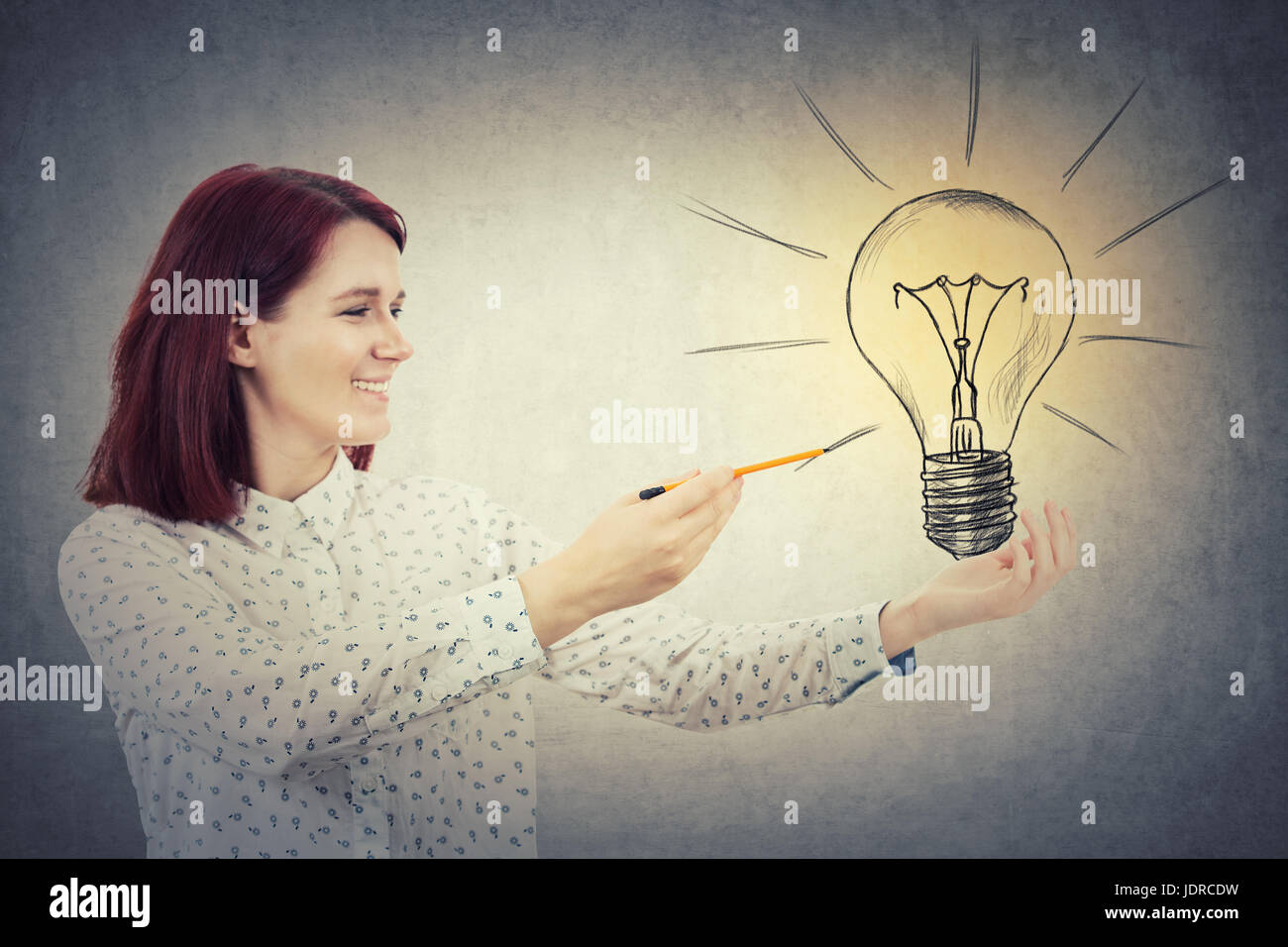 Young smiling girl drawing glowing light bulb sketch in her palm ...