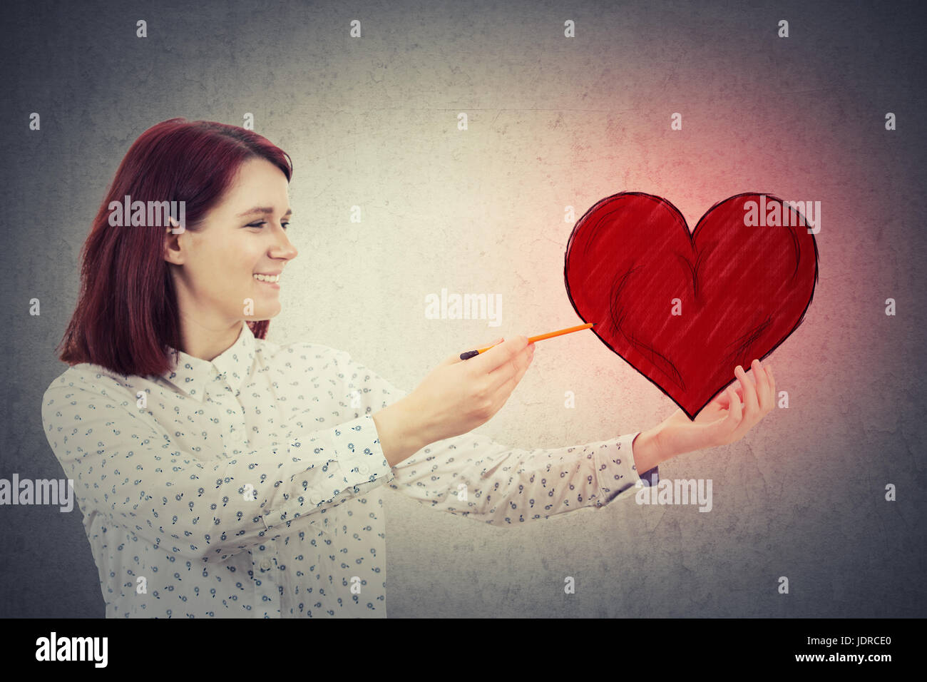 Young smiling girl drawing a doodle heart shape in her palm. Valentine ...