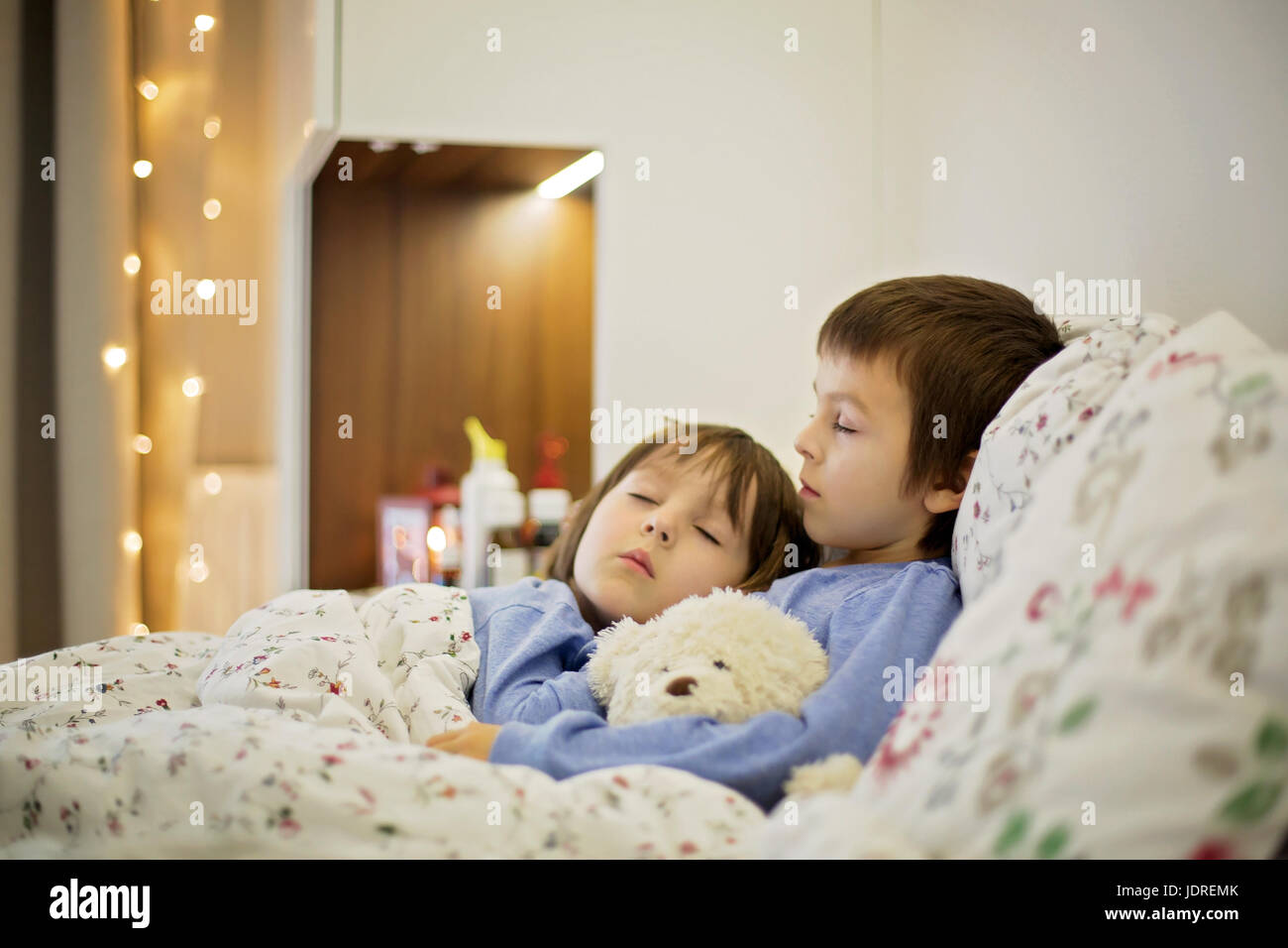 Two cute sick children, boys, staying in bed with fever, playing with ...